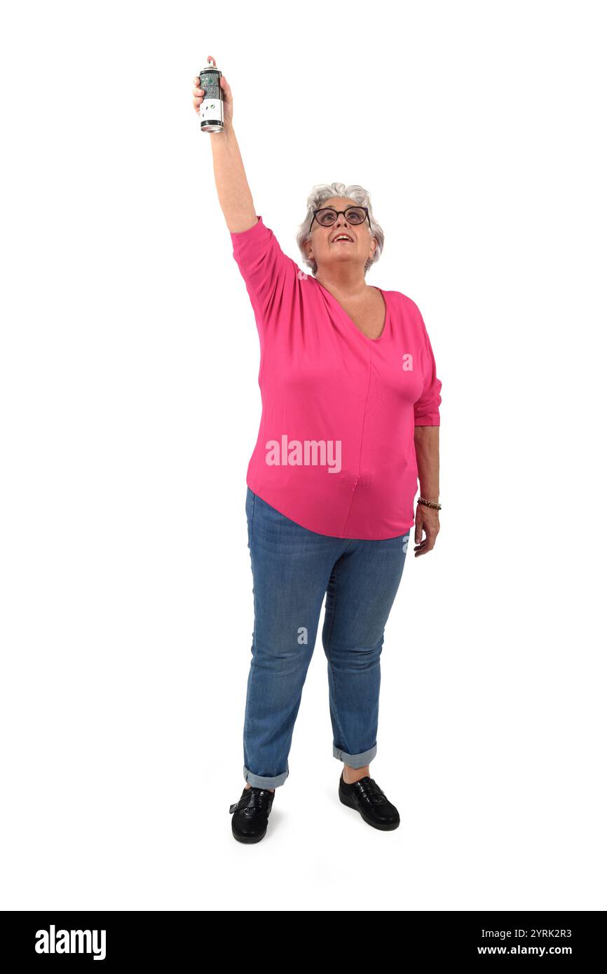 front view of a senior woman spray painting with arms raised on white ...