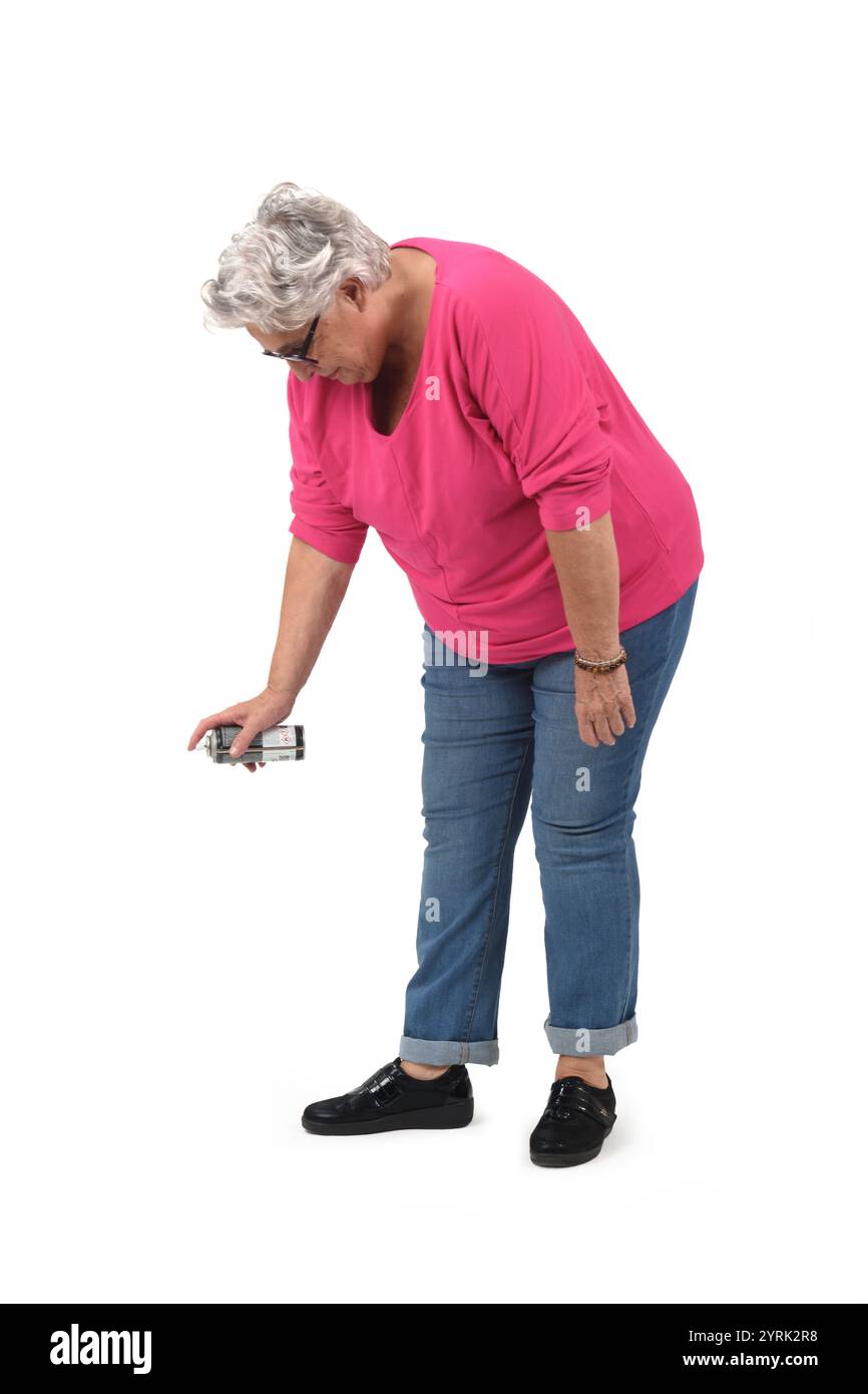 side view of crouched senior woman painting with spray on white ...