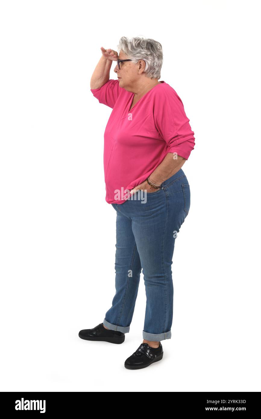 side view of standing senior woman looking at camera with hand on ...