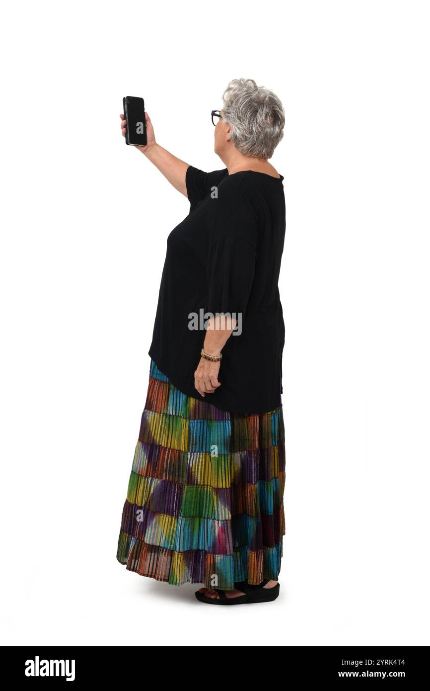back side view of a senior woman taking a self-portrait on white ...