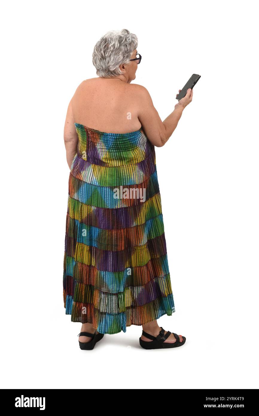 back view of an older woman standing talking on a mobile phone on white ...