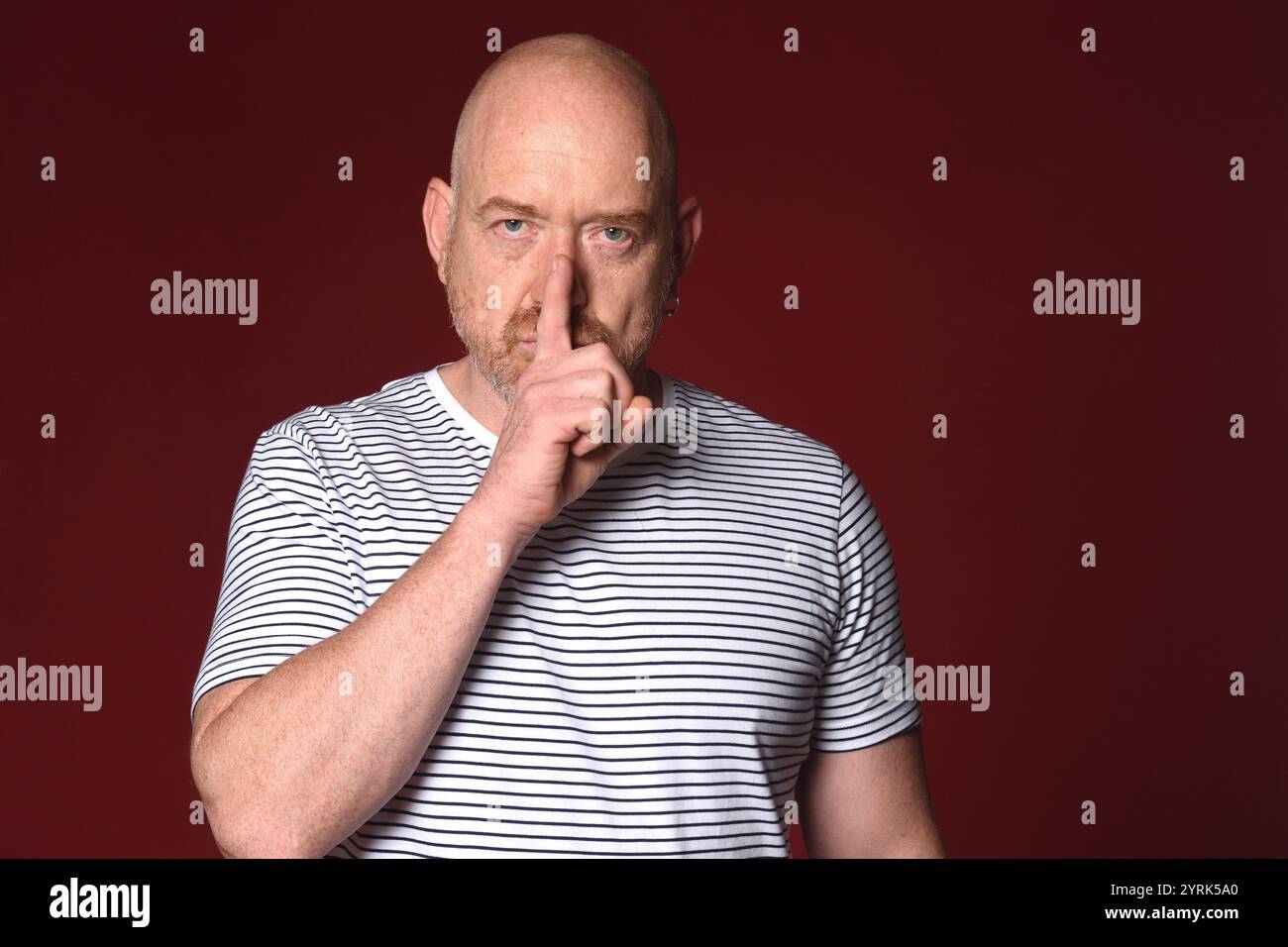 man showing silence sign with fingers on red background Stock Photo - Alamy