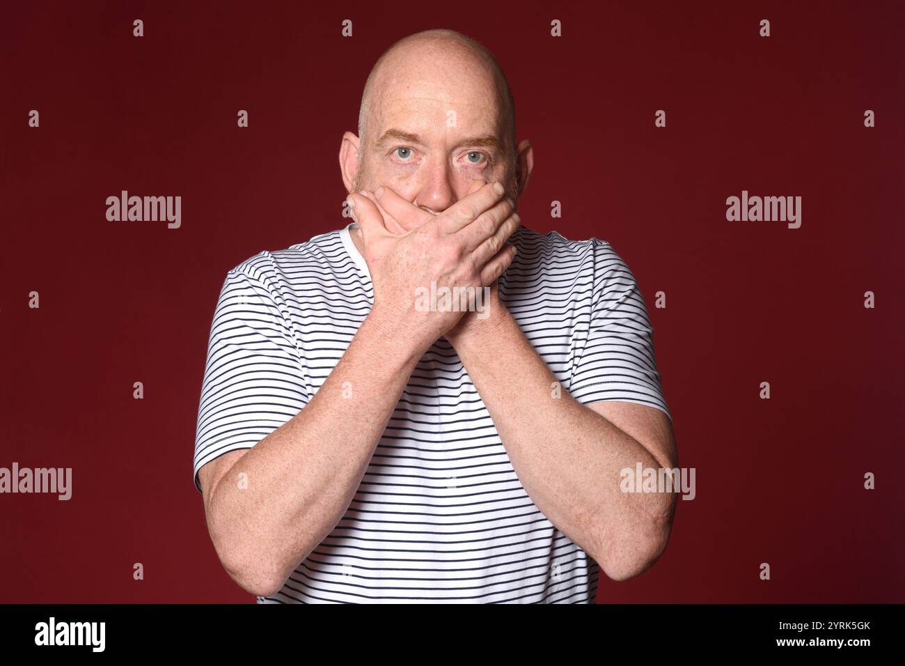 man covering his mouth on red background Stock Photo - Alamy