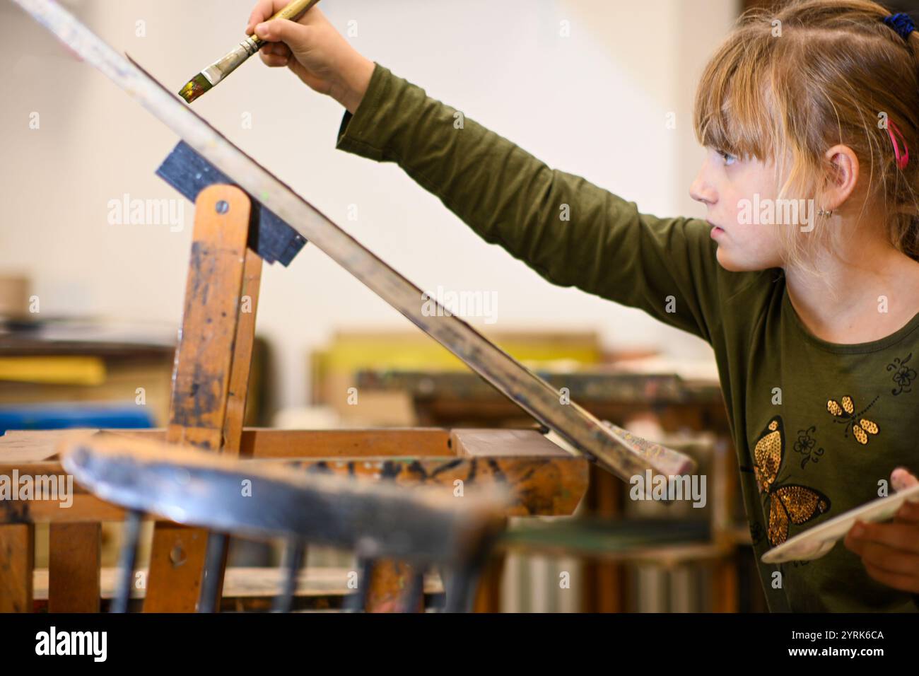 Elementary school student painting abstract art on canvas using ...