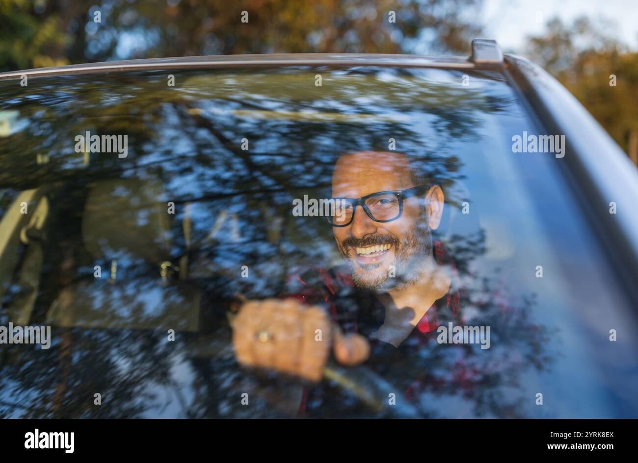 Portrait of handsome smiling man looking through window on driver seat ...