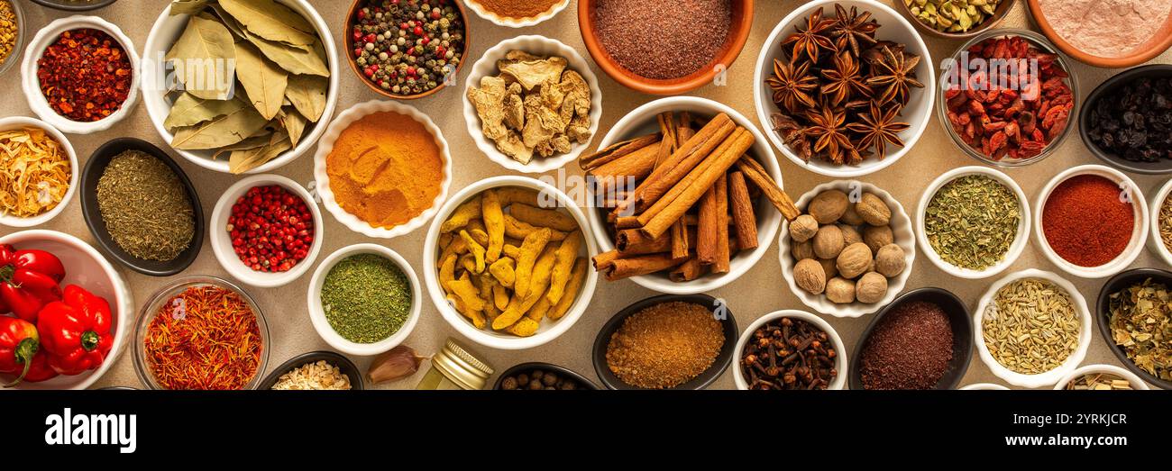 Collection of assorted spices and herbs spread on a beige background ...
