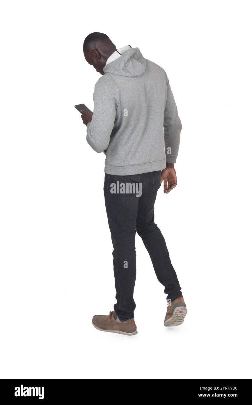 back,side view of a man walking and looking at smartphone on white ...