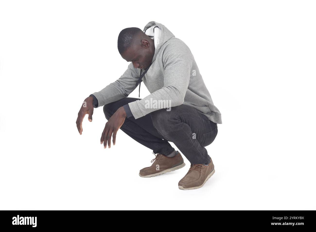 side view of man squatting and looking down on white background Stock ...