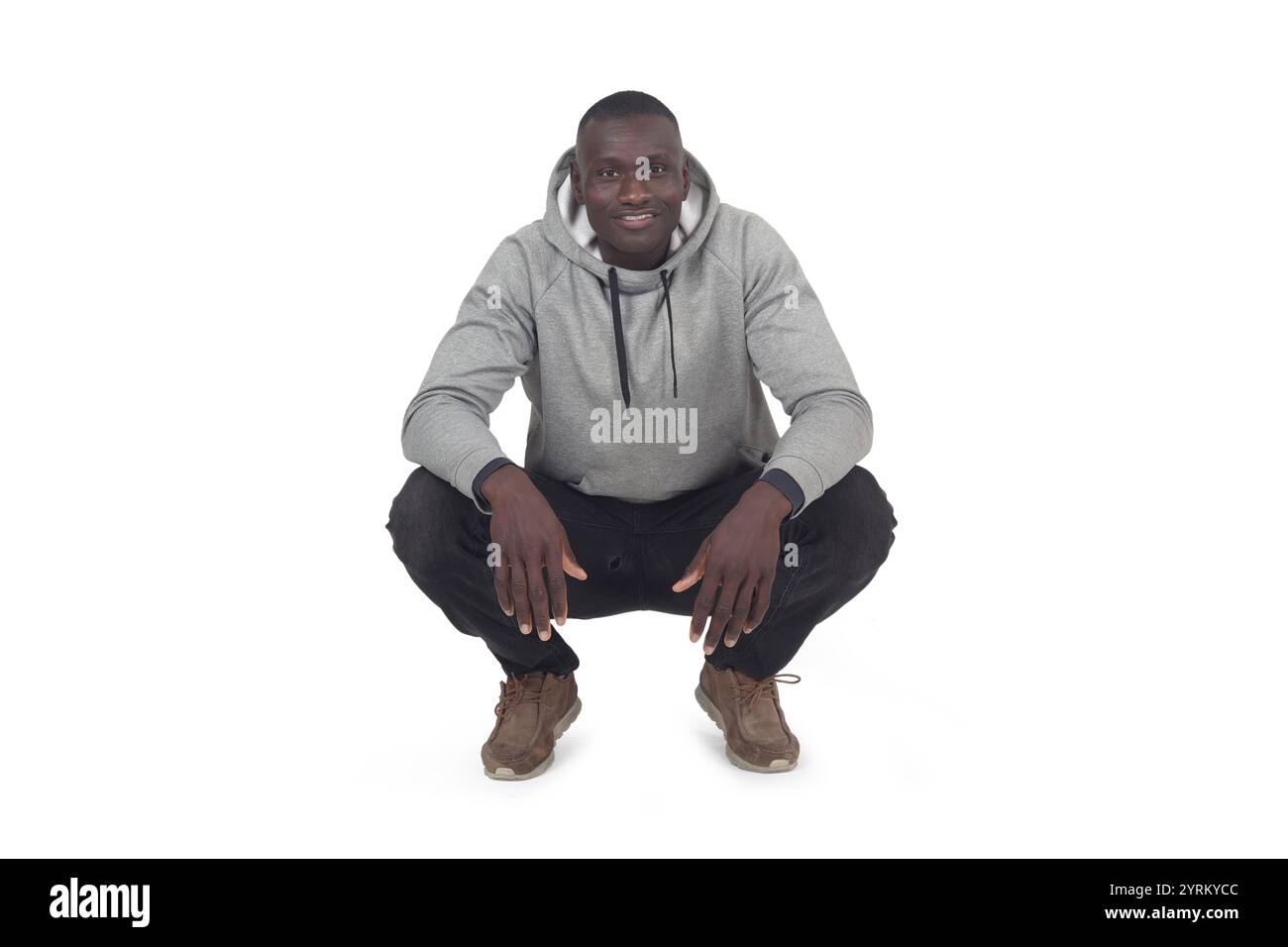 front view of man squatting and looking at camera on white background ...