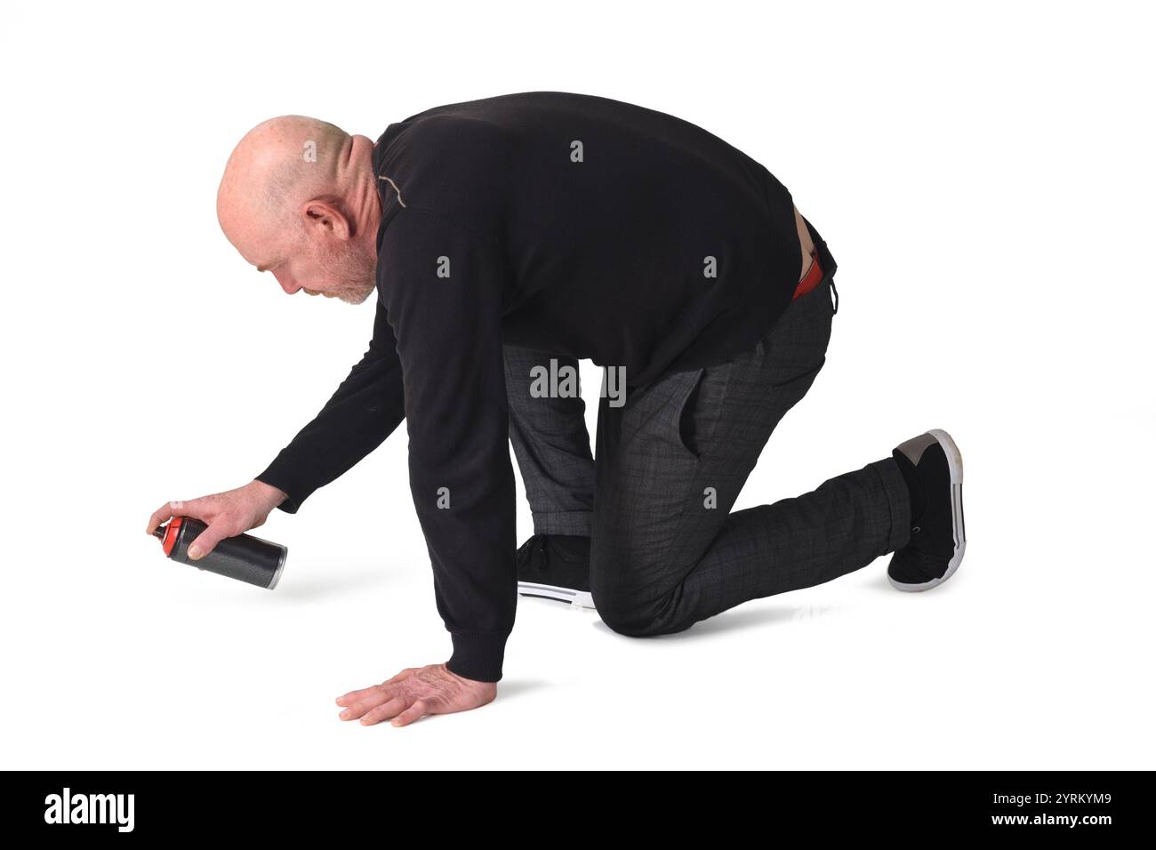side view of a man painting on the floor with spray on white background ...