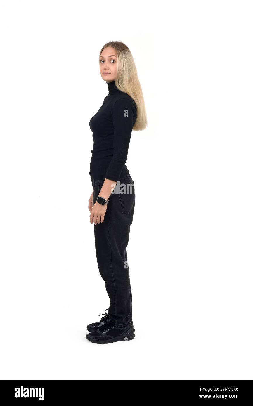 side view of serious woman standing and lookig at camera on white ...