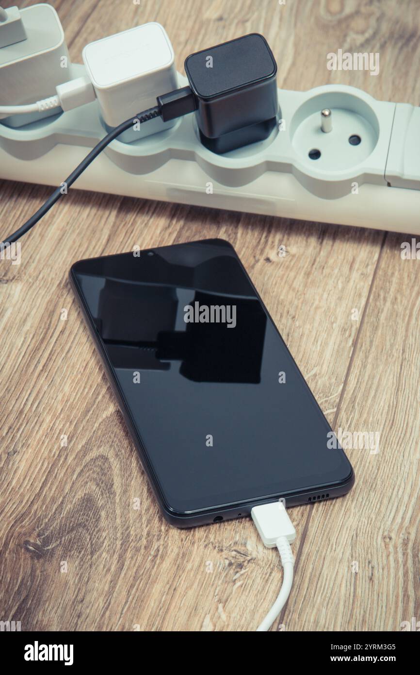 Smartphone, mobile phone and chargers connected to electrical power ...