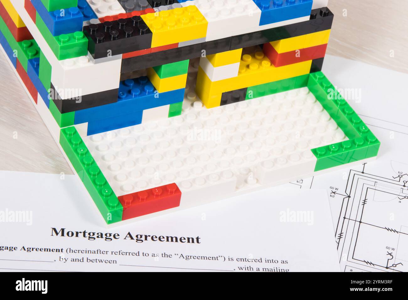 Unfinished house made of colorful toy blocks and mortgage agreement ...
