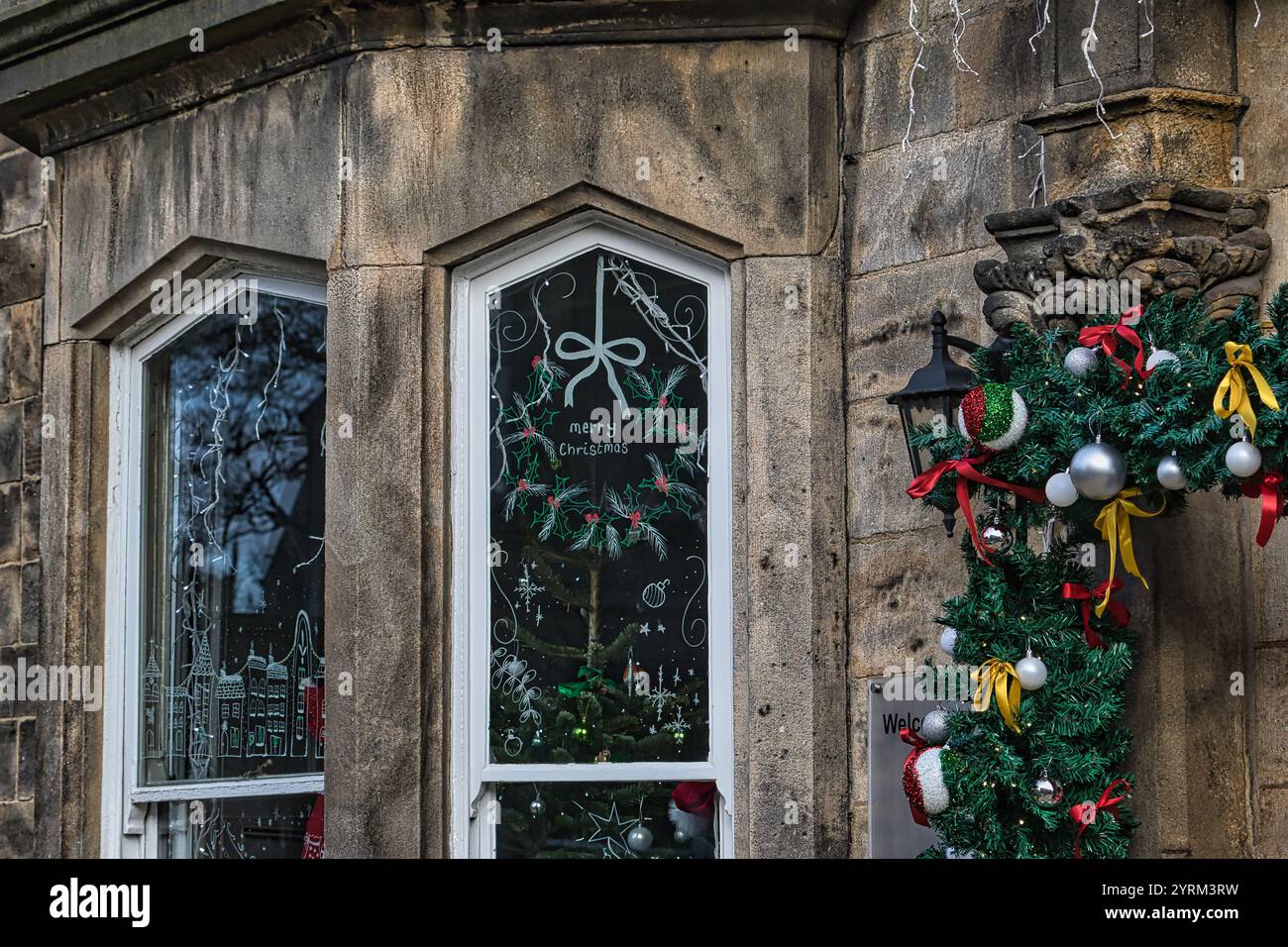 A stone building's bay window displays Christmas decorations. The ...