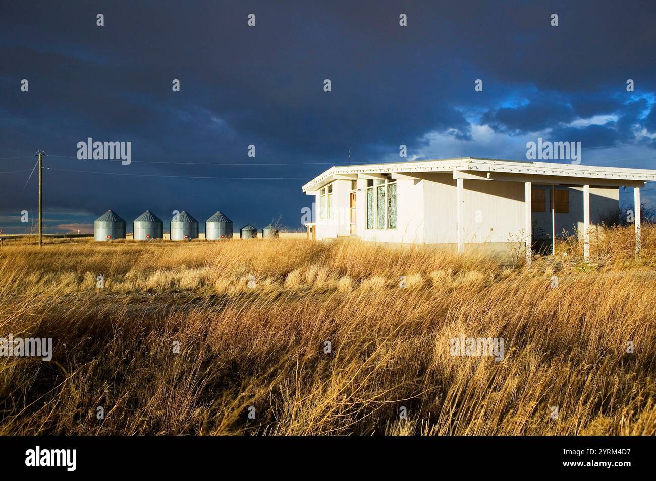 Grain silos and abandoned house, landscape with dramatic sky. Stand Off ...