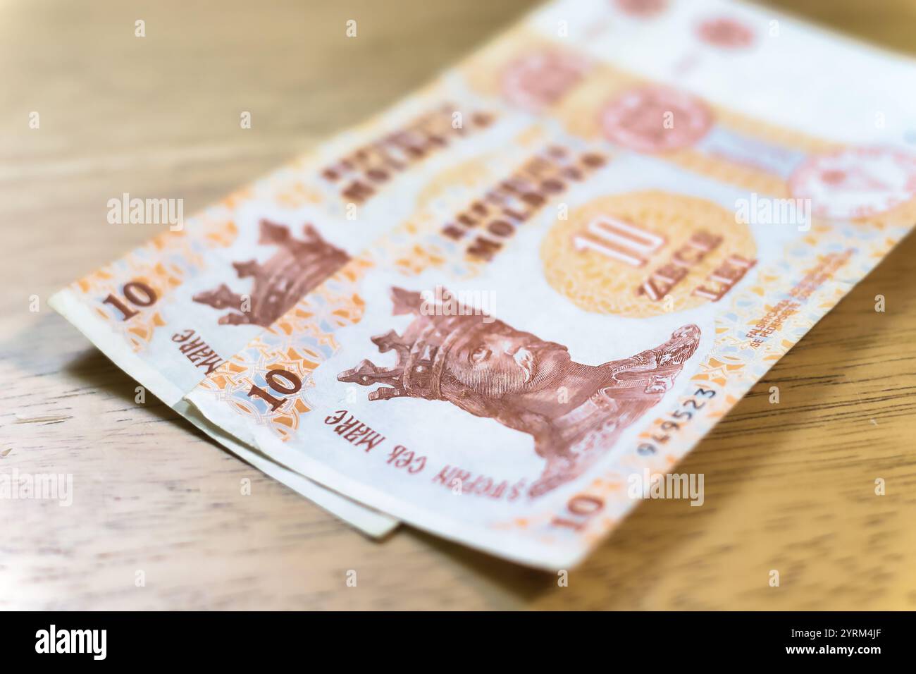 Close-up of two Moldovan 10 Lei banknotes lying on a light brown wooden ...