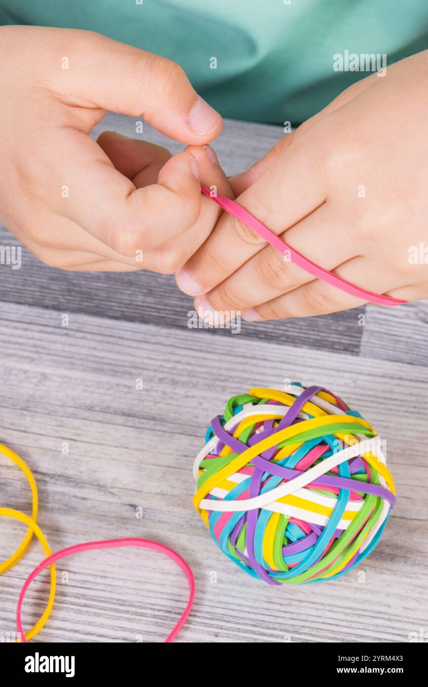Preschooler hands with ball of colorful rubber bands or erasers ...