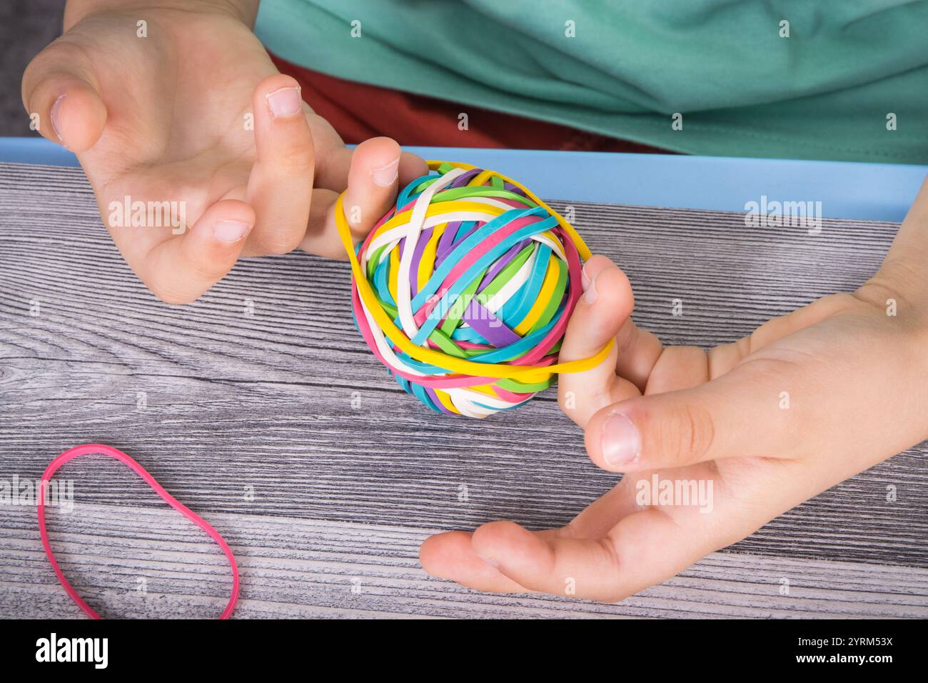 Preschooler hands with ball of colorful rubber bands or erasers ...