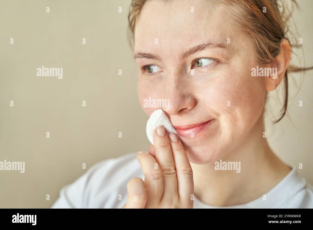 Woman pampering skin with cotton pad for perfect complexion in modern ...