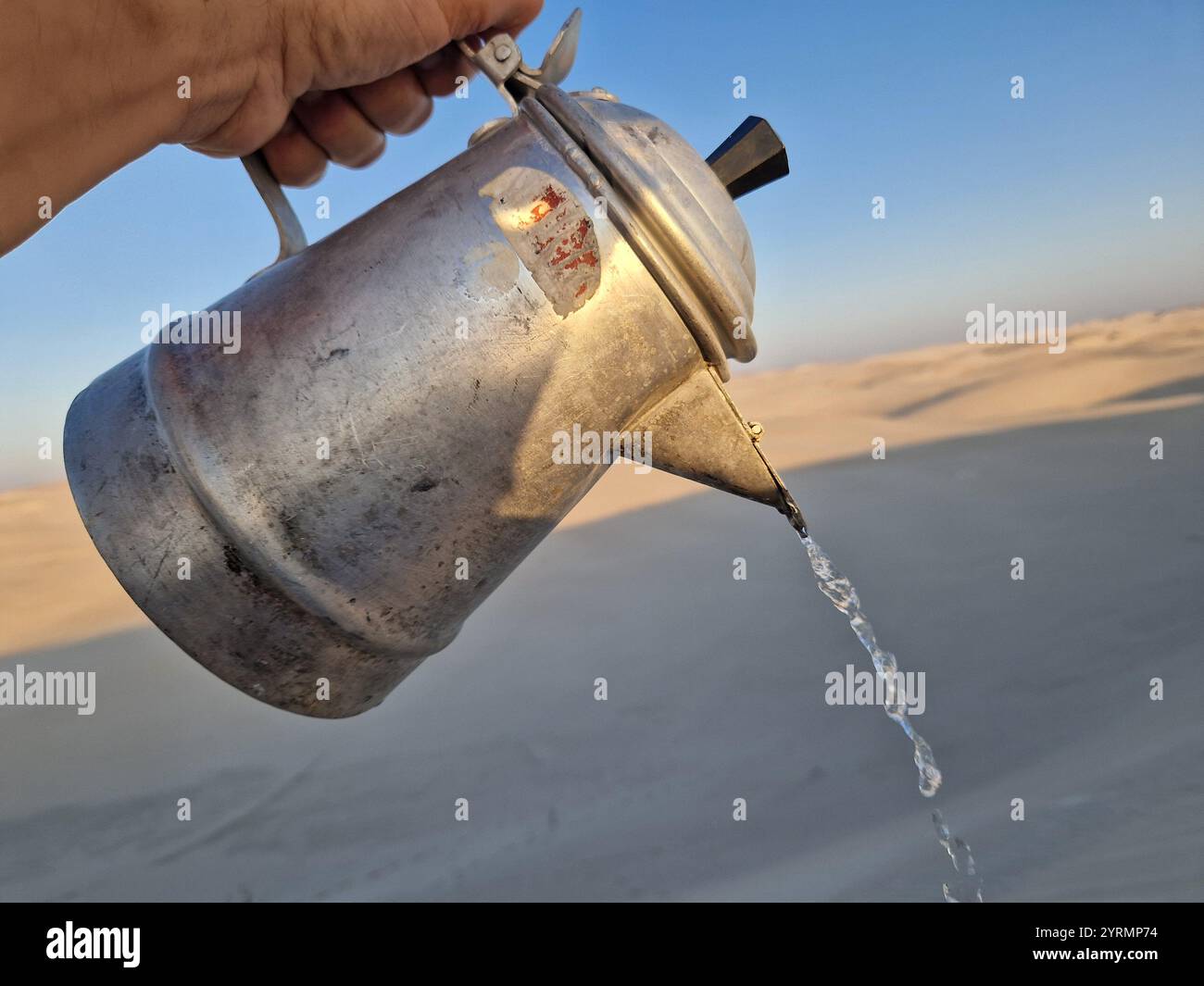 Hand holding an aluminium water kettle in his hand and pours water to ...