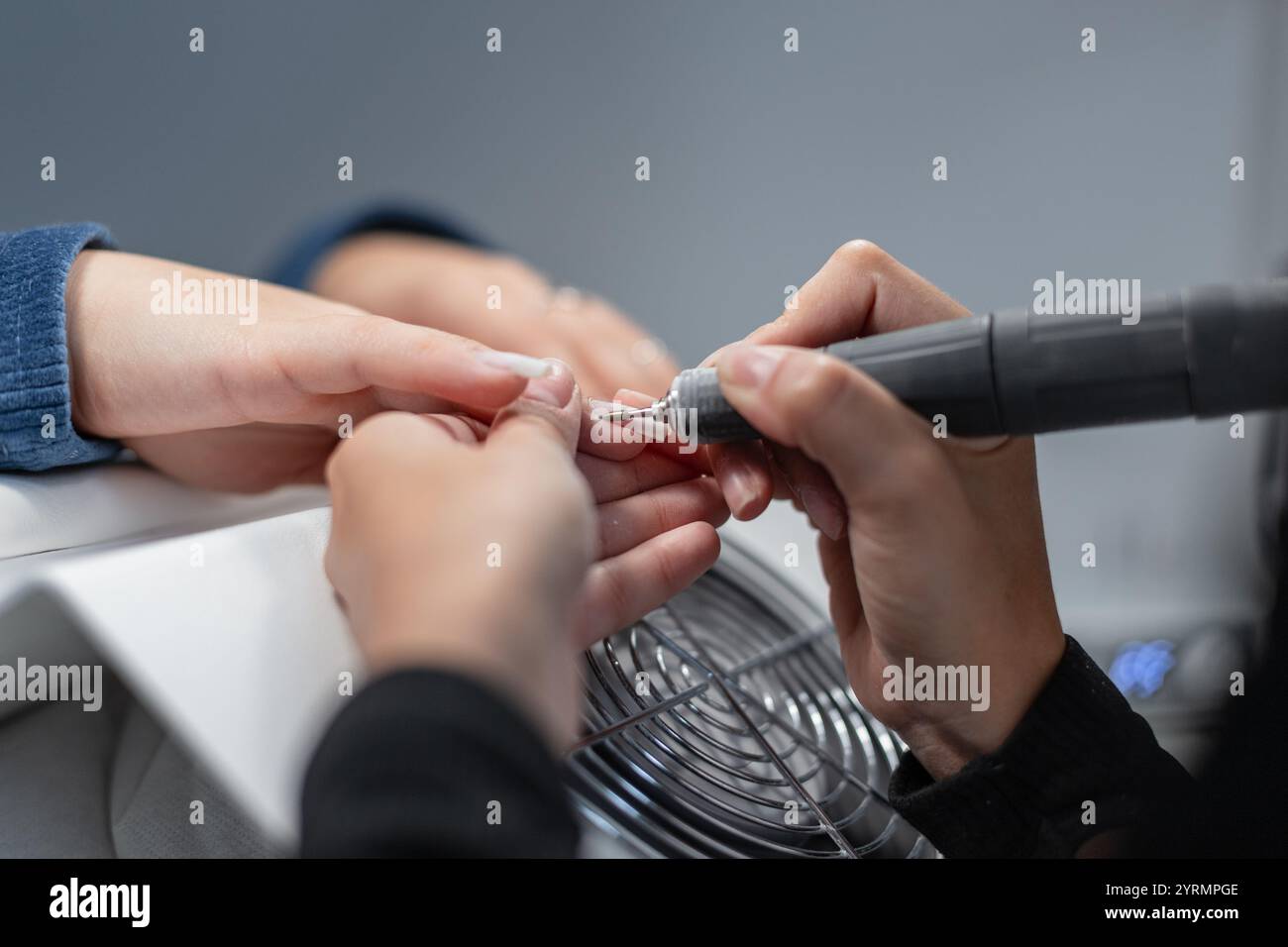 Professional manicurist girl doing manicure and filing nail with drill ...