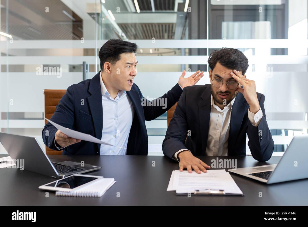 Angry colleague yelling at a stressed employee in a modern office ...