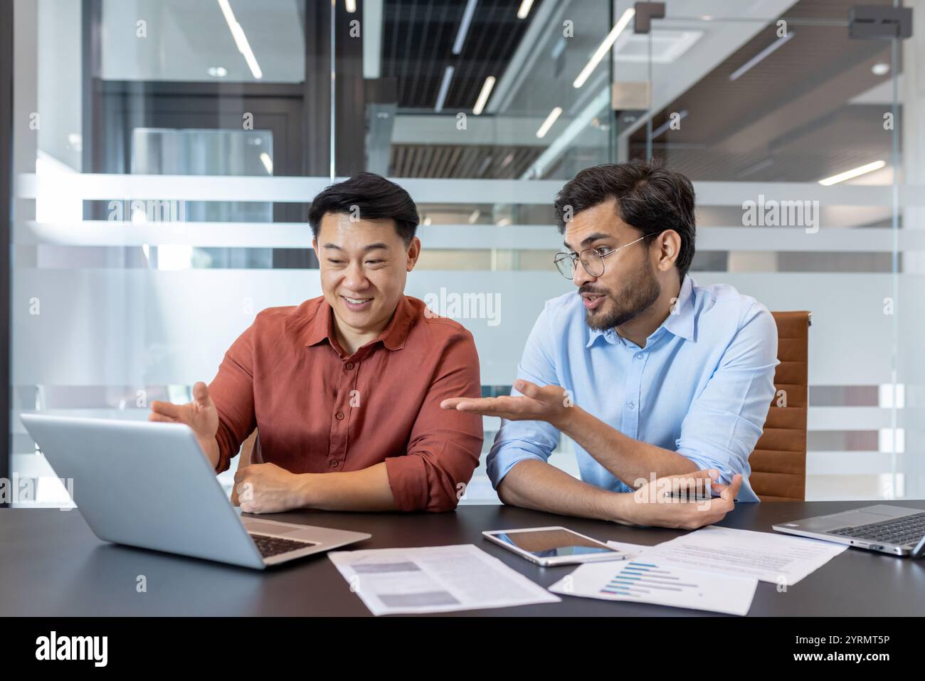 Two colleagues engaged in a lively discussion at a modern office table ...