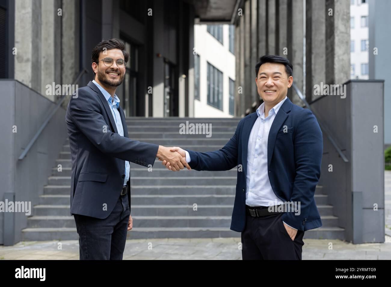 Two business professionals in formal attire exchange a confident ...