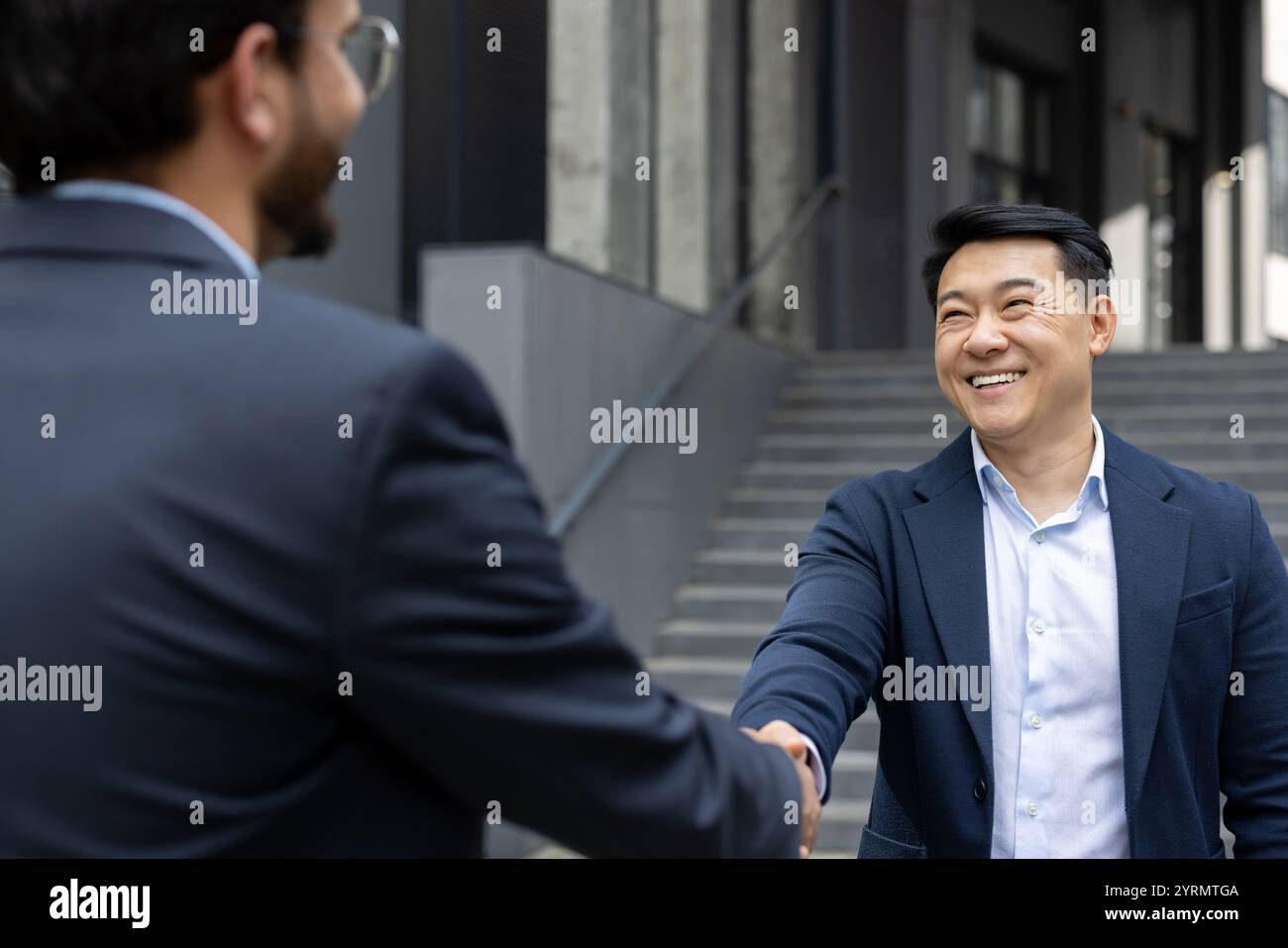 Two business professionals in formal attire shaking hands, symbolizing ...