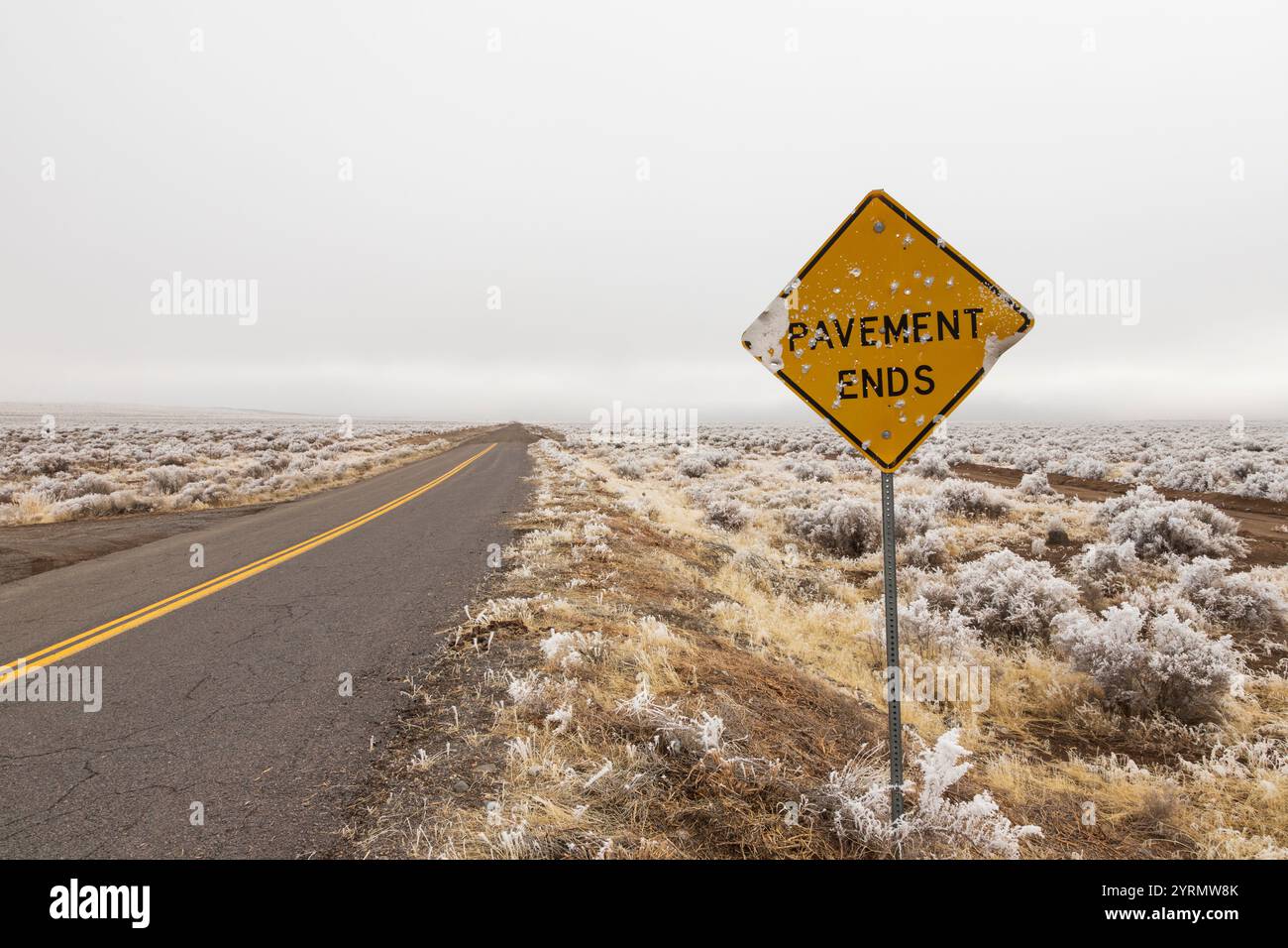 A bullet riddled and weathered sign indicates the pavement ending as ...