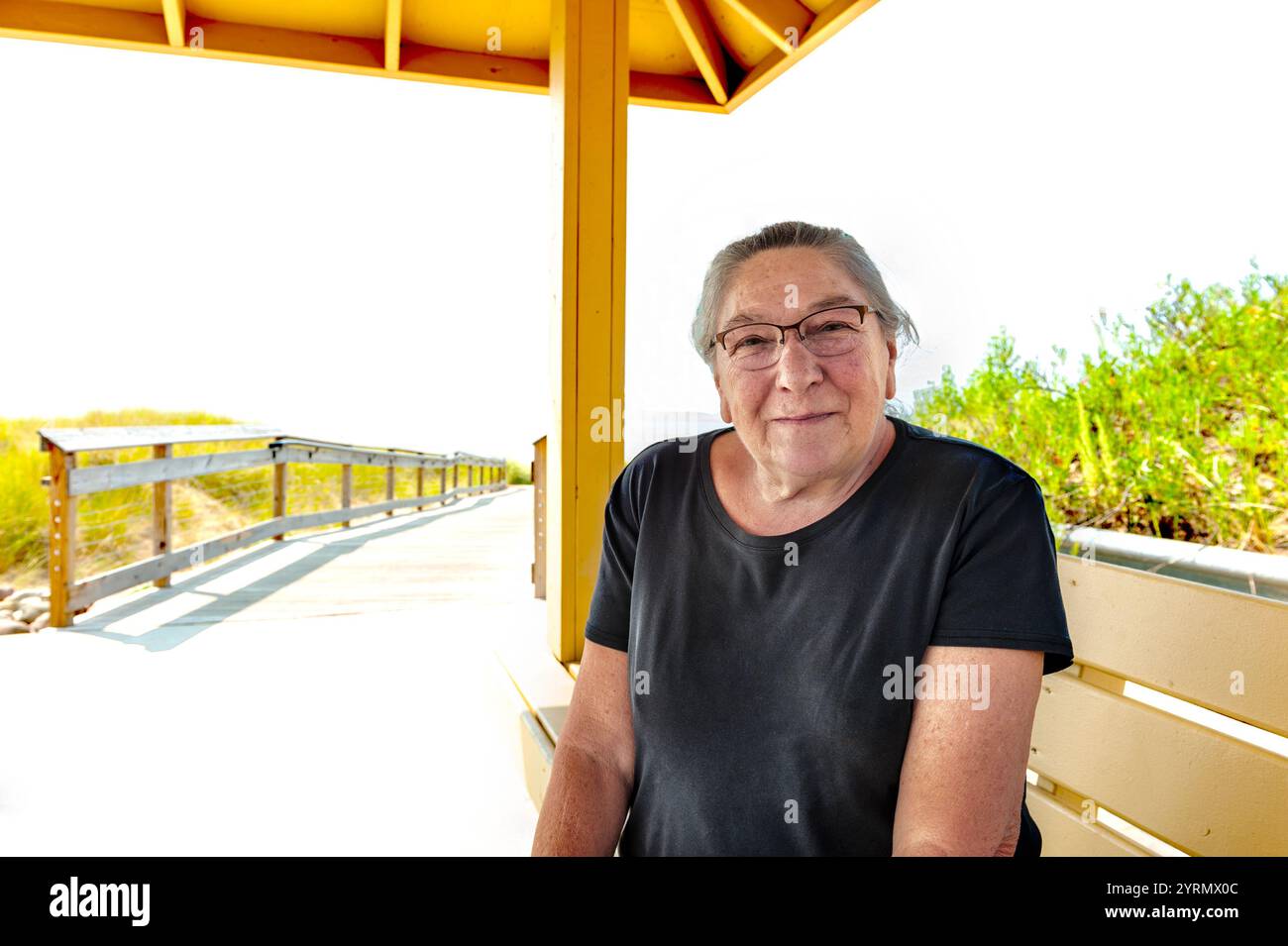 Senior woman sitting and relaxing at Portage Point Beach on a sunny ...