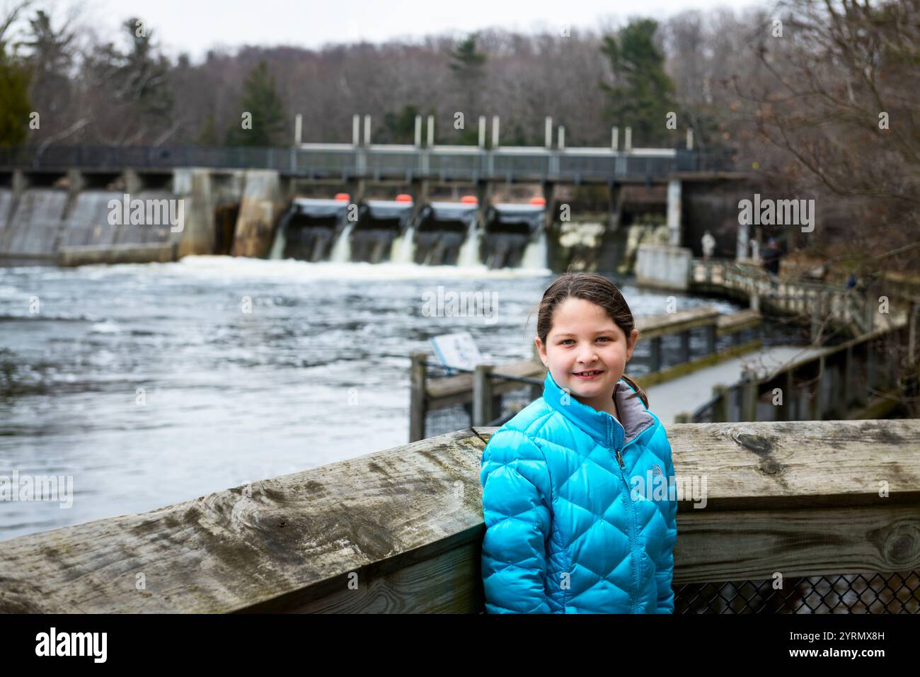 Girl posing for the camera with the Hamlin Lake dam behind during a ...