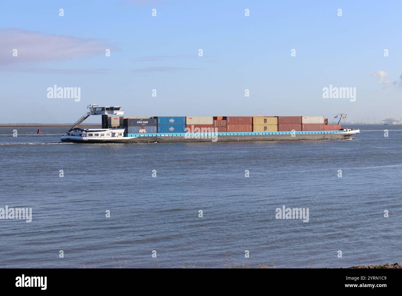a barge is sailing with containers in a river and a blue sky Stock ...
