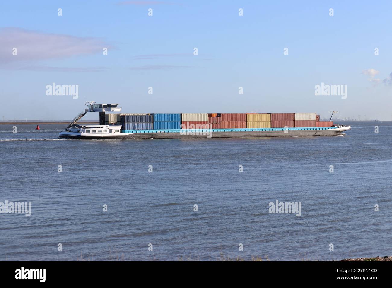 a barge with two high containers is sailing at a river and doing inland ...