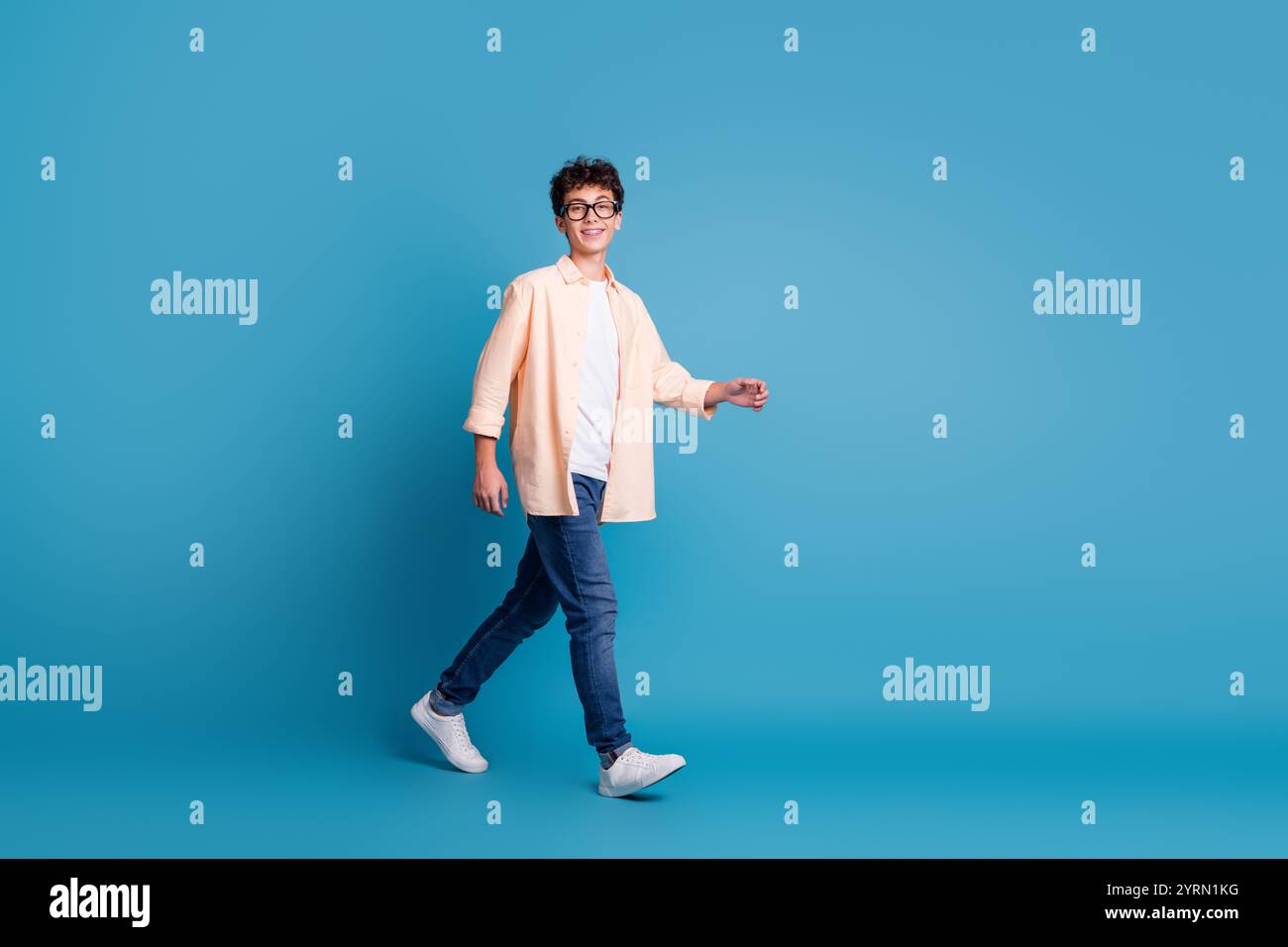 Confident young man walking with a smile in casual style against blue ...