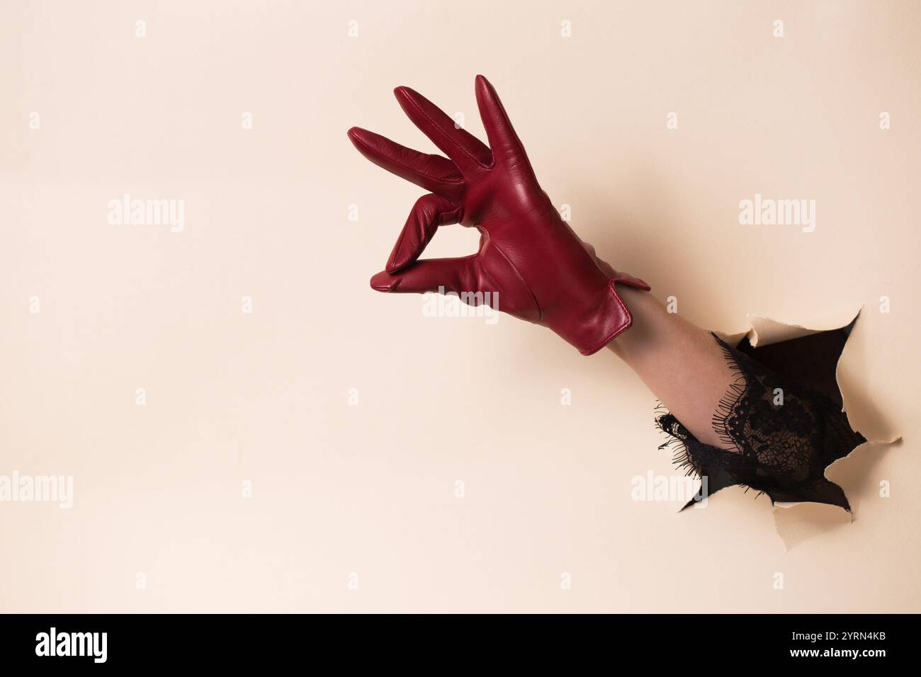 A woman's hand in a leather glove shows a gesture. The hand is pushed ...