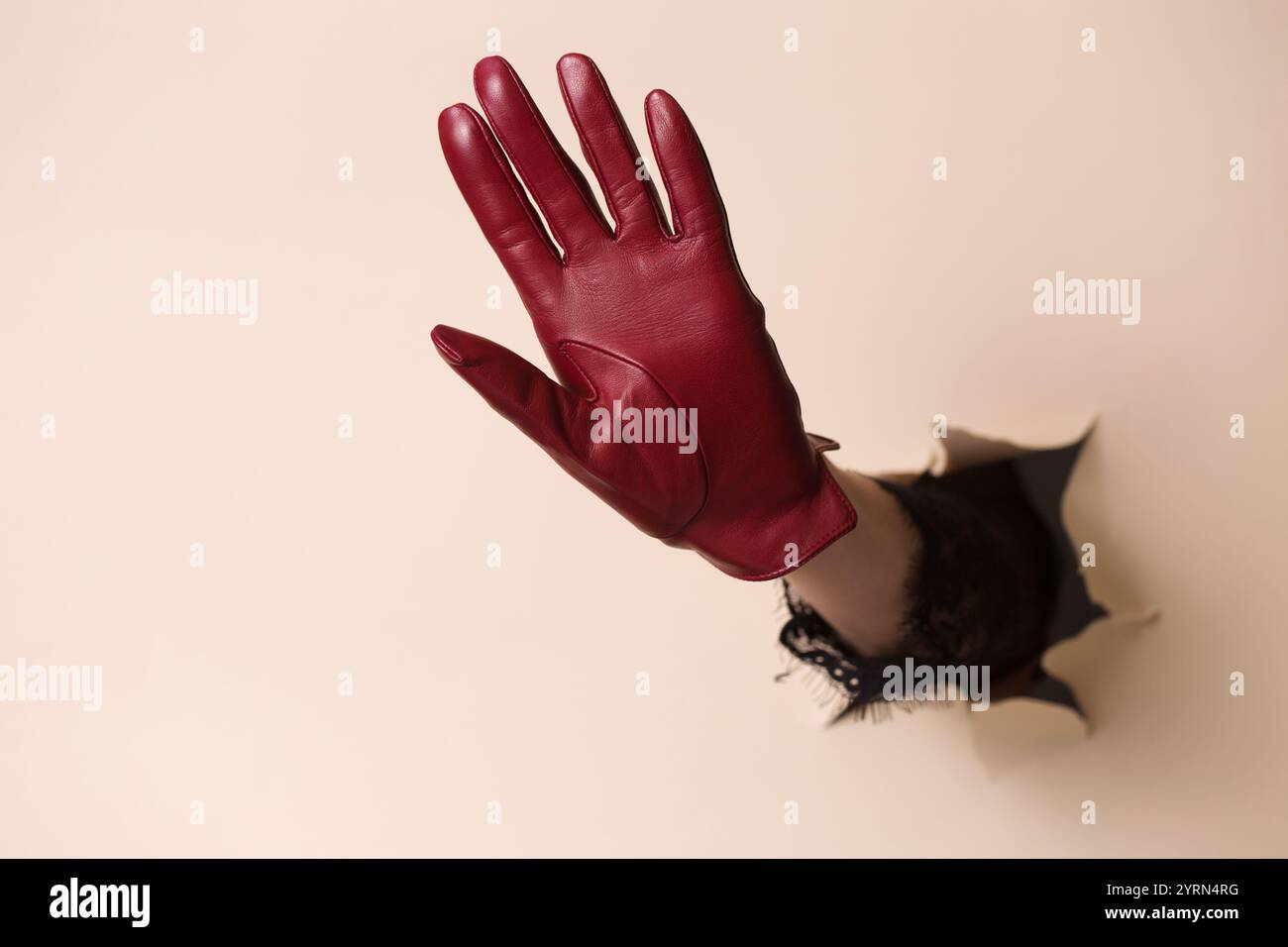 A woman's hand in a leather glove shows a gesture. The hand is pushed ...