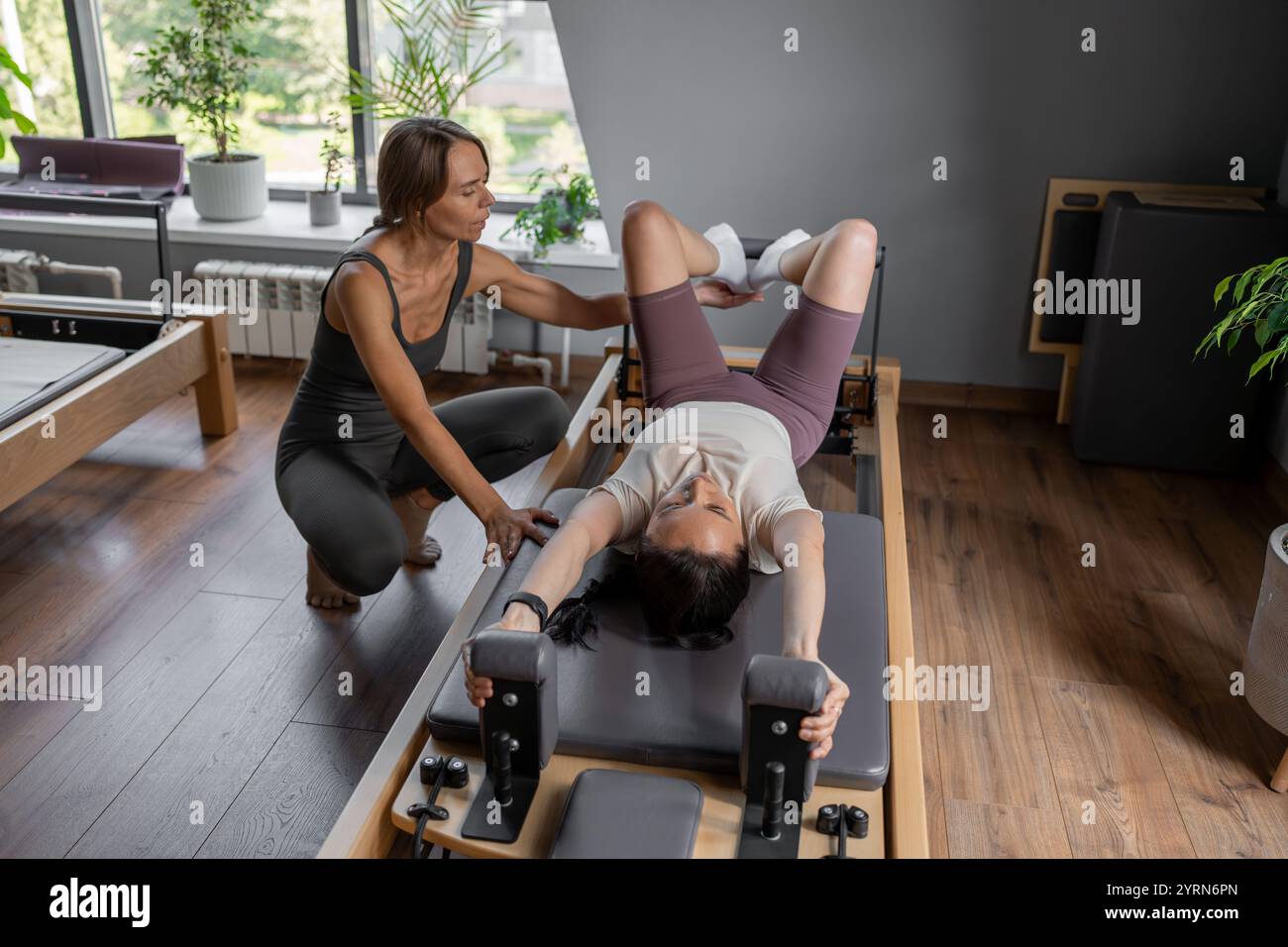 A Pilates Instructor helps a client with stretching exercises on ...