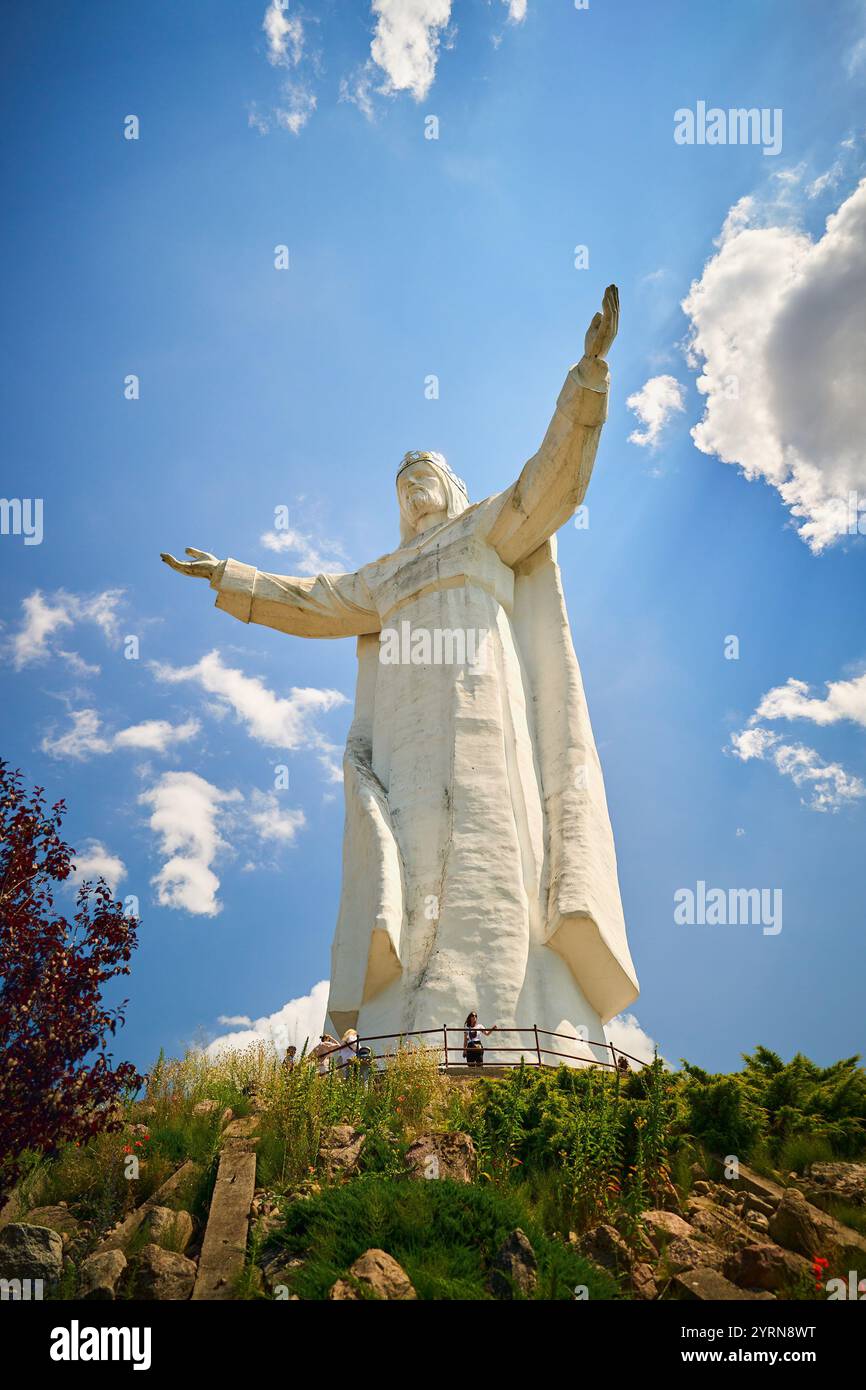 A towering statue of Christ with outstretched arms against a backdrop ...