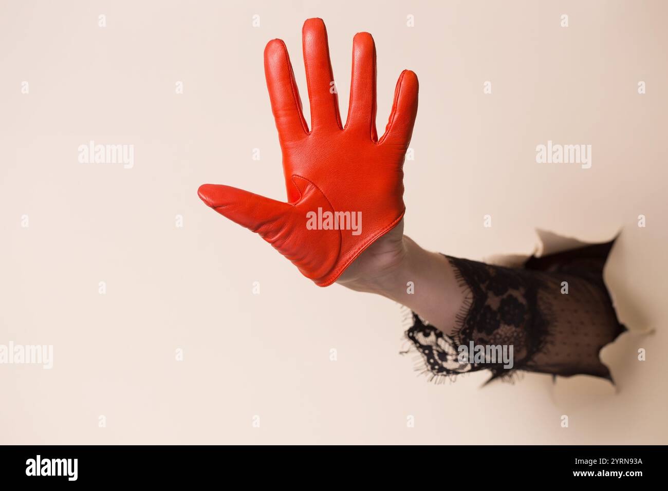 A woman's hand in a leather glove shows a gesture. The hand is pushed ...