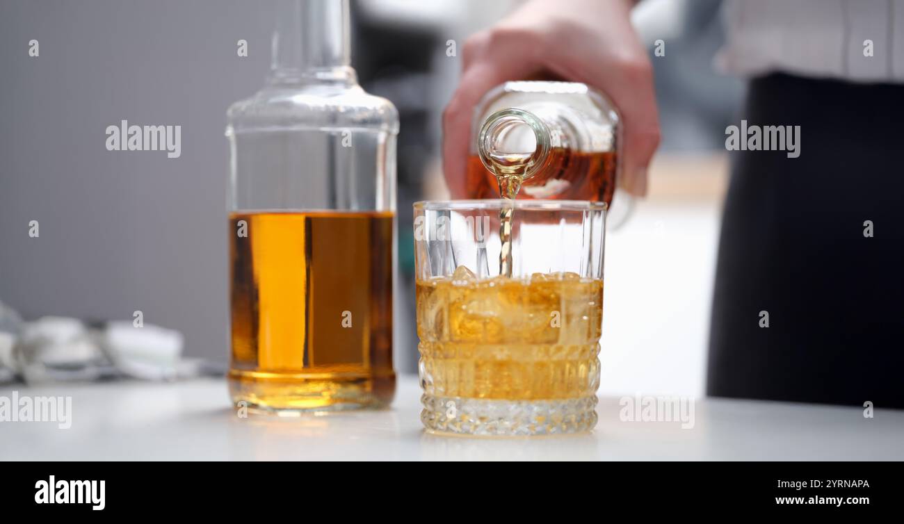 A hand pours a brown alcoholic drink into a glass Stock Photo - Alamy