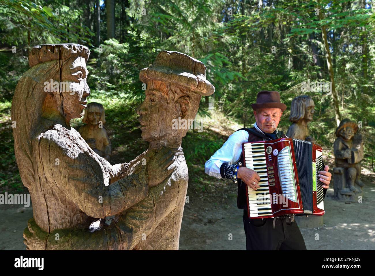 musician amidst wooden statues along the outdoor wooden sculpture ...