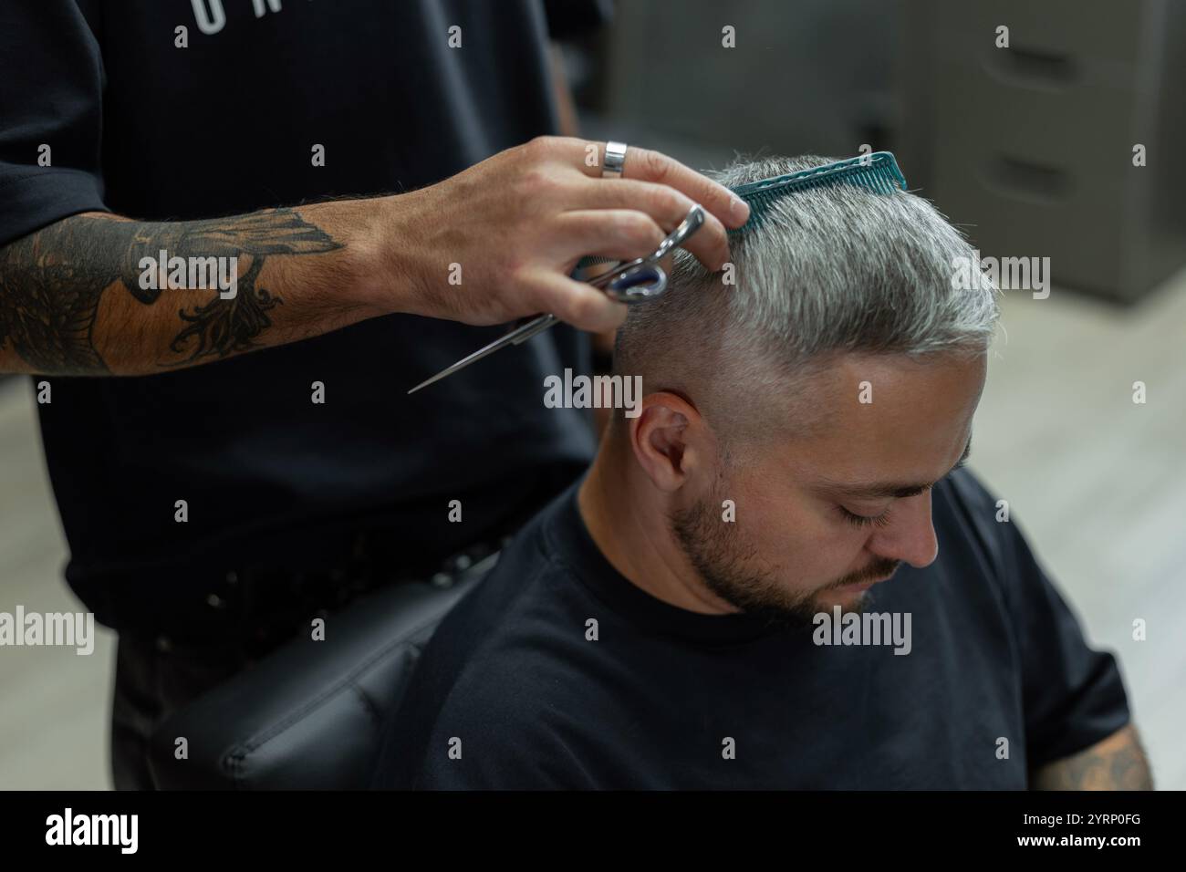 Male hairdresser cutting guy with short gray hair with scissors and ...