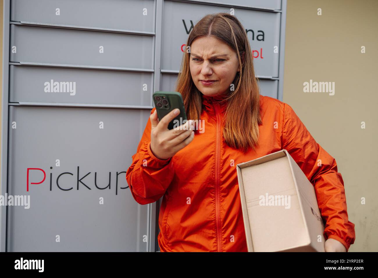 Young angry woman picks up parcel from automatic post office machine ...