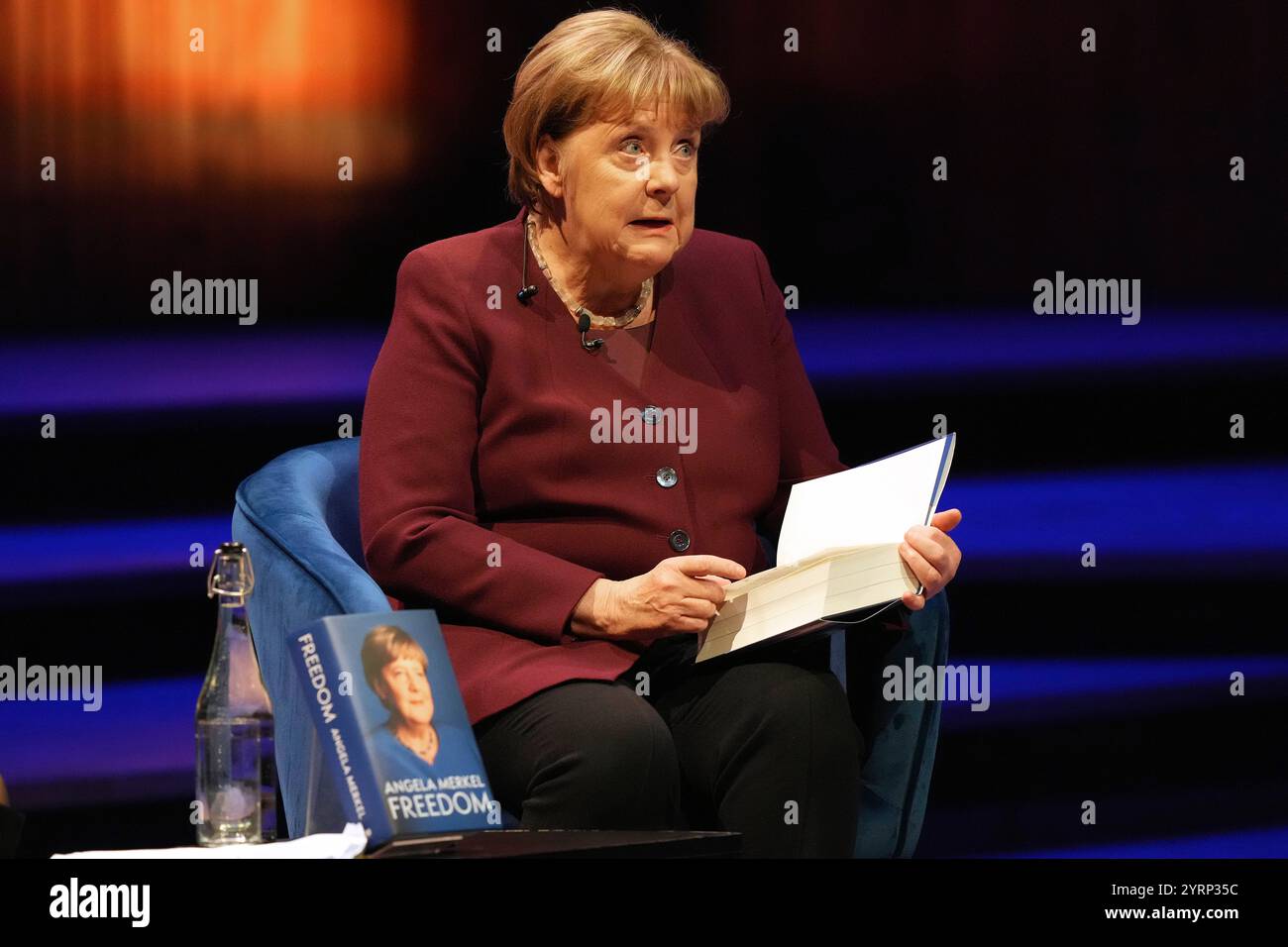 Former German Chancellor Angela Merkel reads in her book during a ...