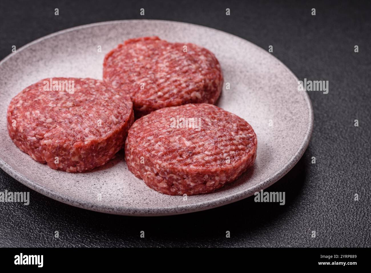 Fresh raw ground beef burger patty with salt and spices on textured ...