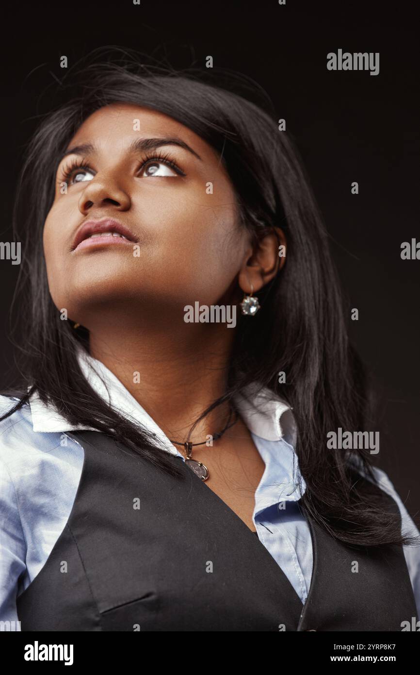Studio portrait featuring a young indian woman gazing upward, embodying ...