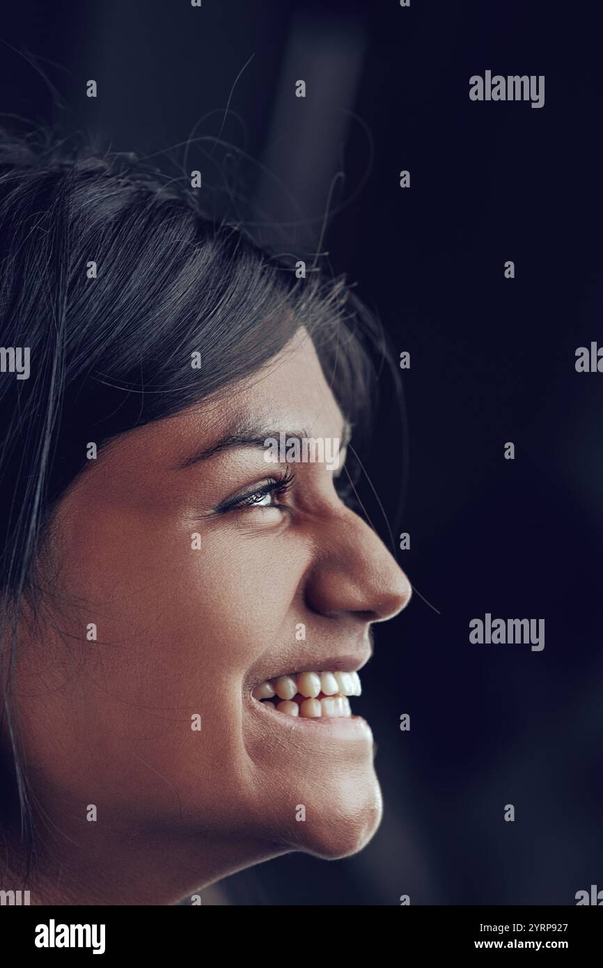 Close-up profile of a young indian woman smiling and gazing upward ...