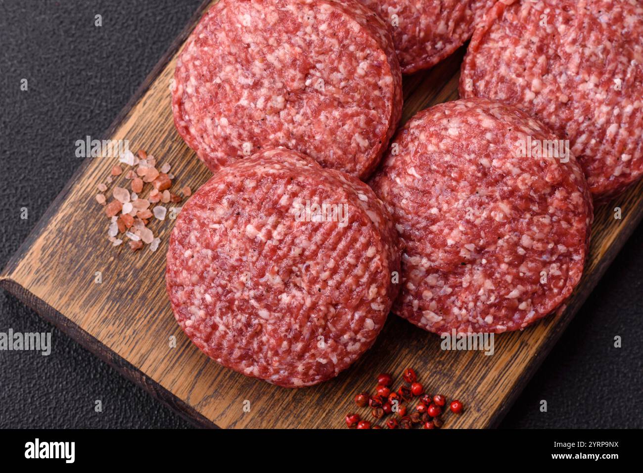 Fresh raw ground beef burger patty with salt and spices on textured ...