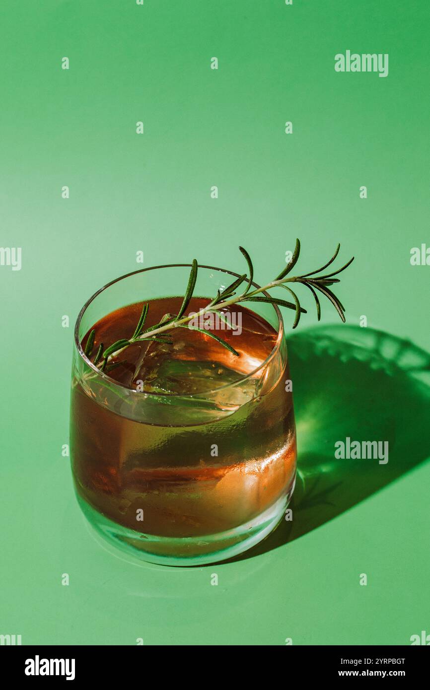 Photo of a dark brown cocktail in a rocks glass, garnished with a sprig ...